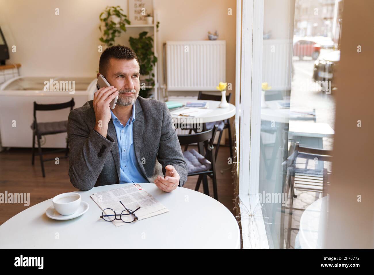 Confident businessman sitting at table in cafe using mobile phone Stock ...