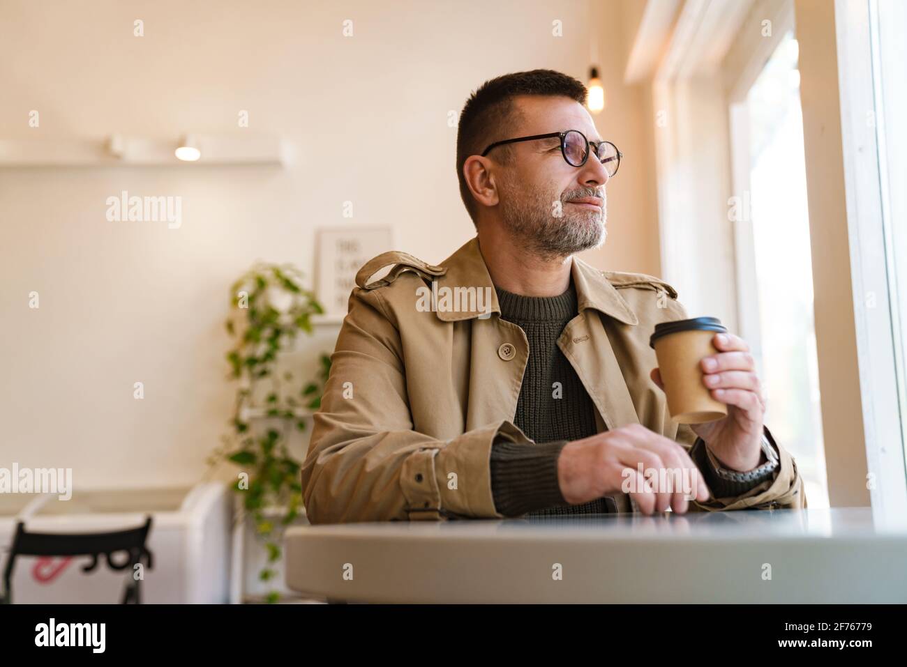 Handsome confident businessman having breakfast in modern coffee shop ...