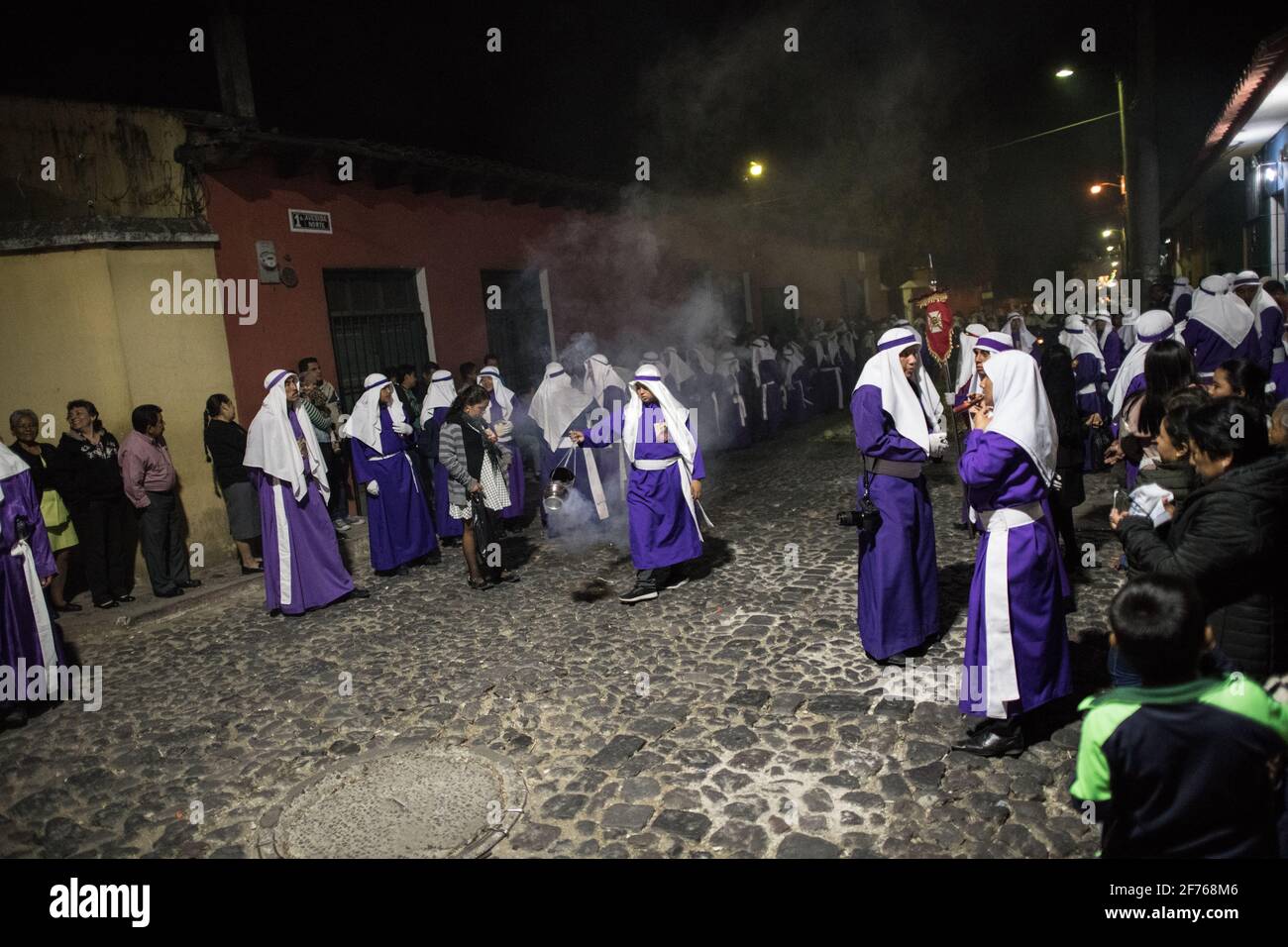 Cucuruchos in purple robes process solemnly through the streets of ...