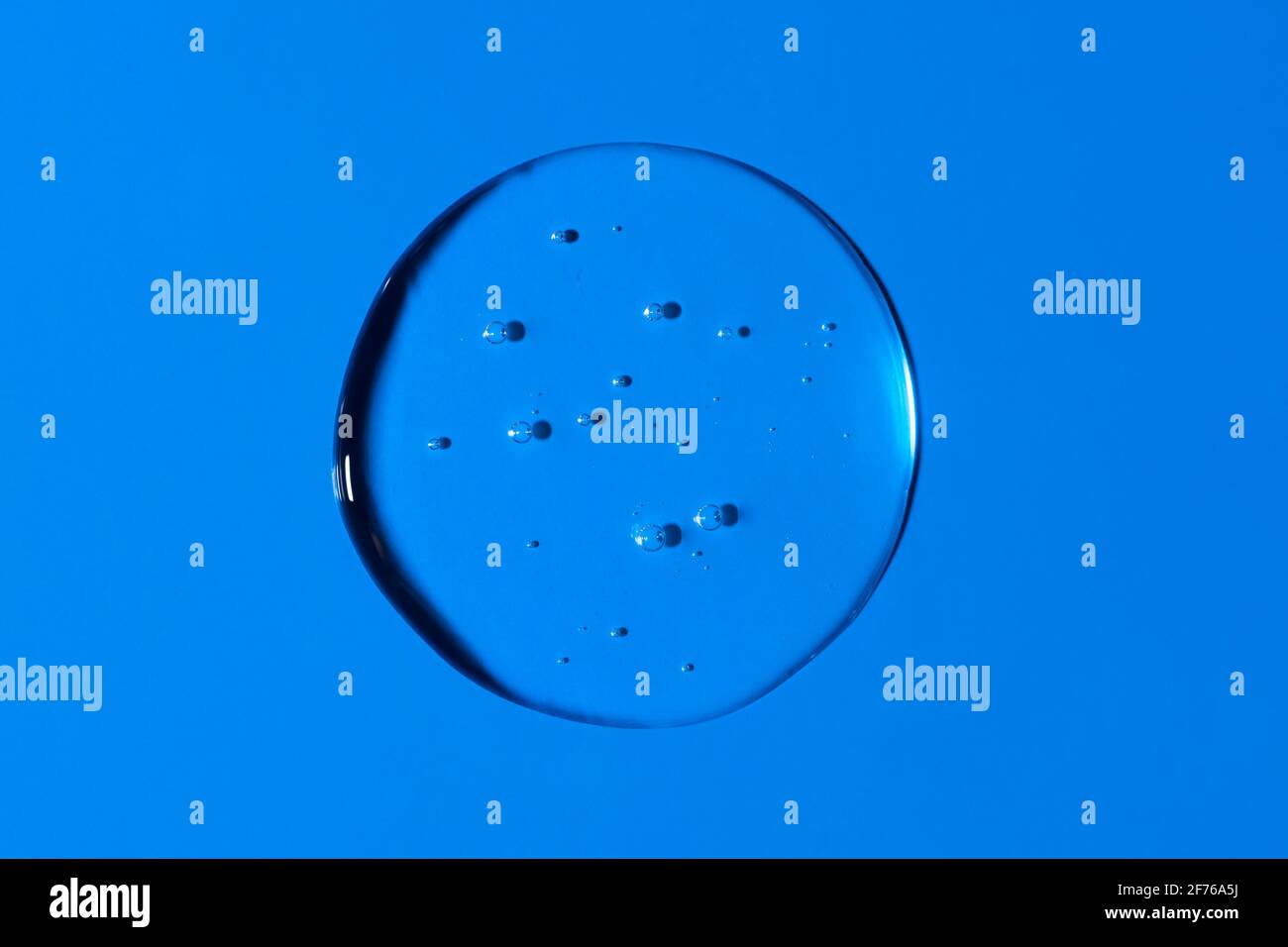Clear transparent round liquid gel drop or smear isolated on blue ...