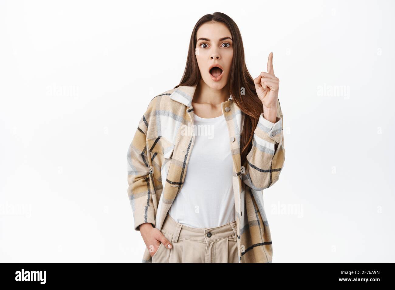 Impressed and surprised young woman pointing finger up and drop jaw ...