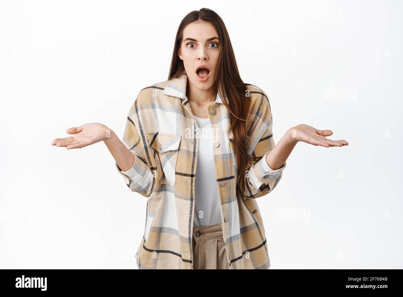 Surprised and confused woman gasp wondered, shrugging and stretch hands ...