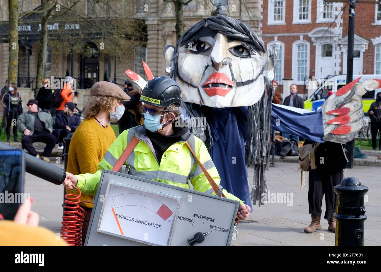 A puppet Priti Patel in the background. Members of the public gather on ...