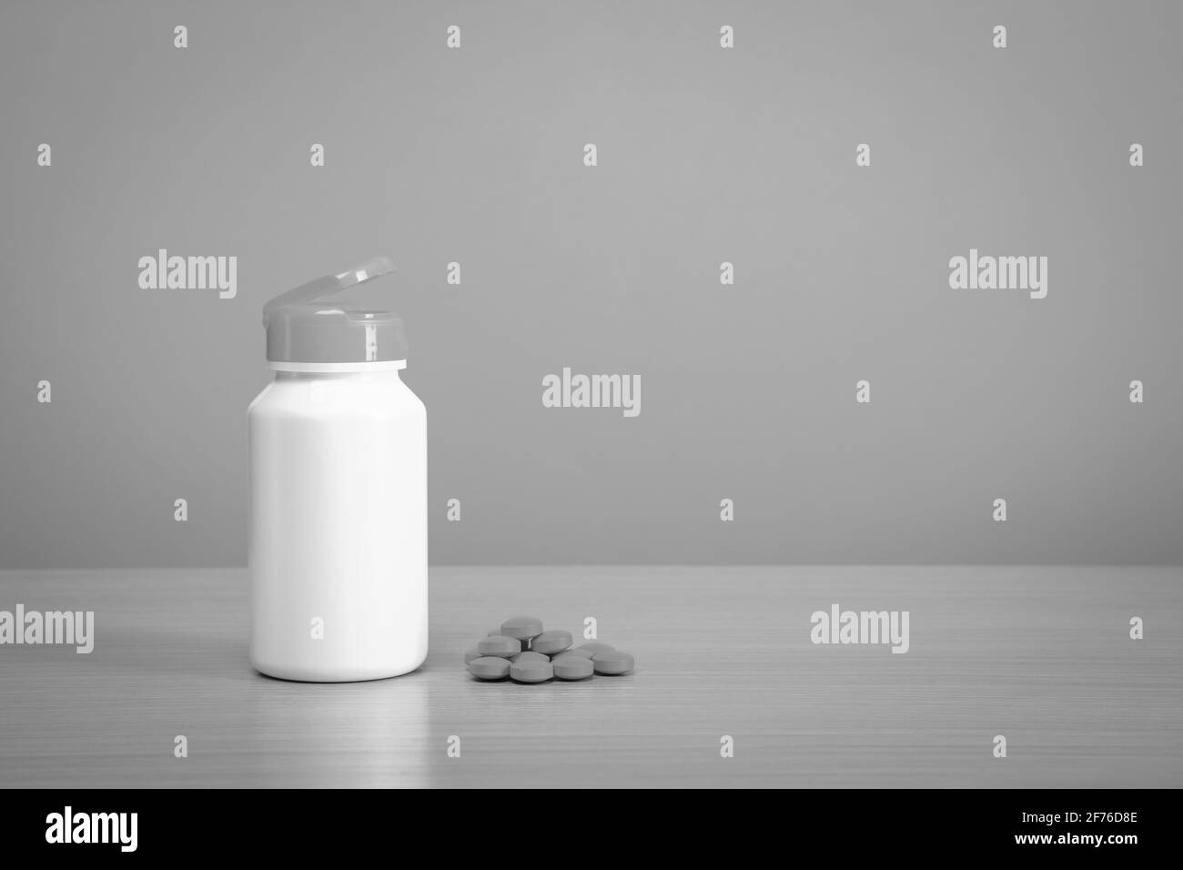 A jar with scattered pills on a gray background. Black and White style ...