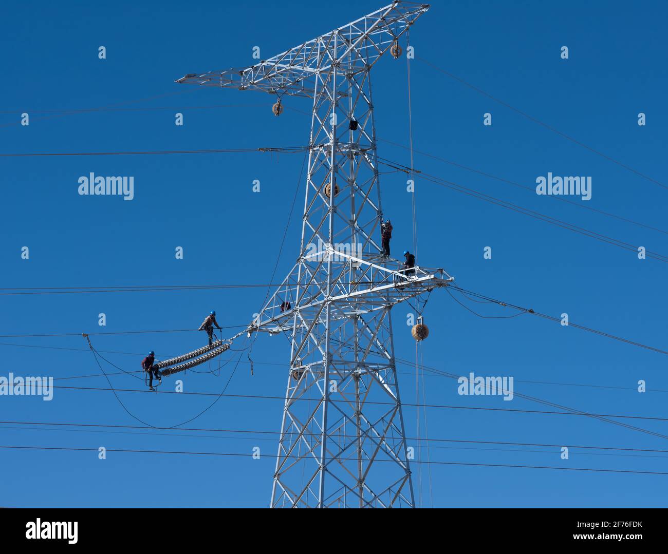 Maintenance workers working on steel towers of high-voltage power lines ...