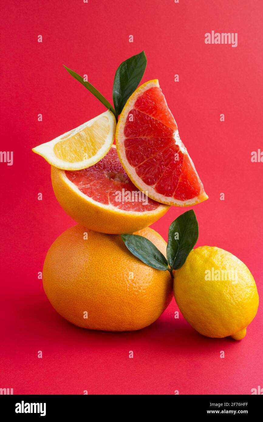 Pyramid of grapefruit and lemon in balance on the red background.Close ...