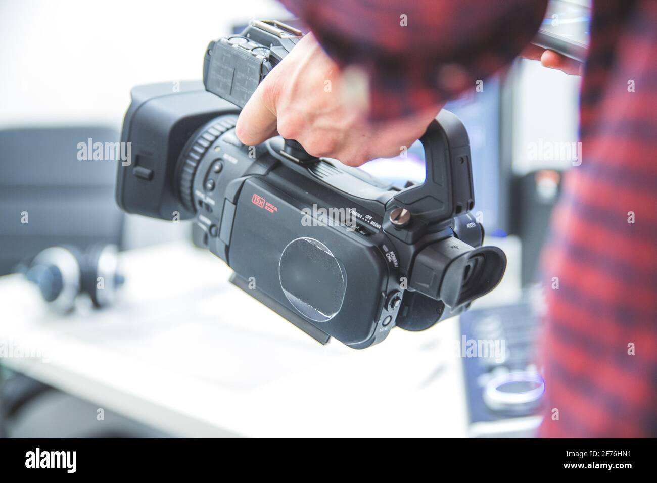 Male cameraman is holding a professional video camcorder, blurry ...