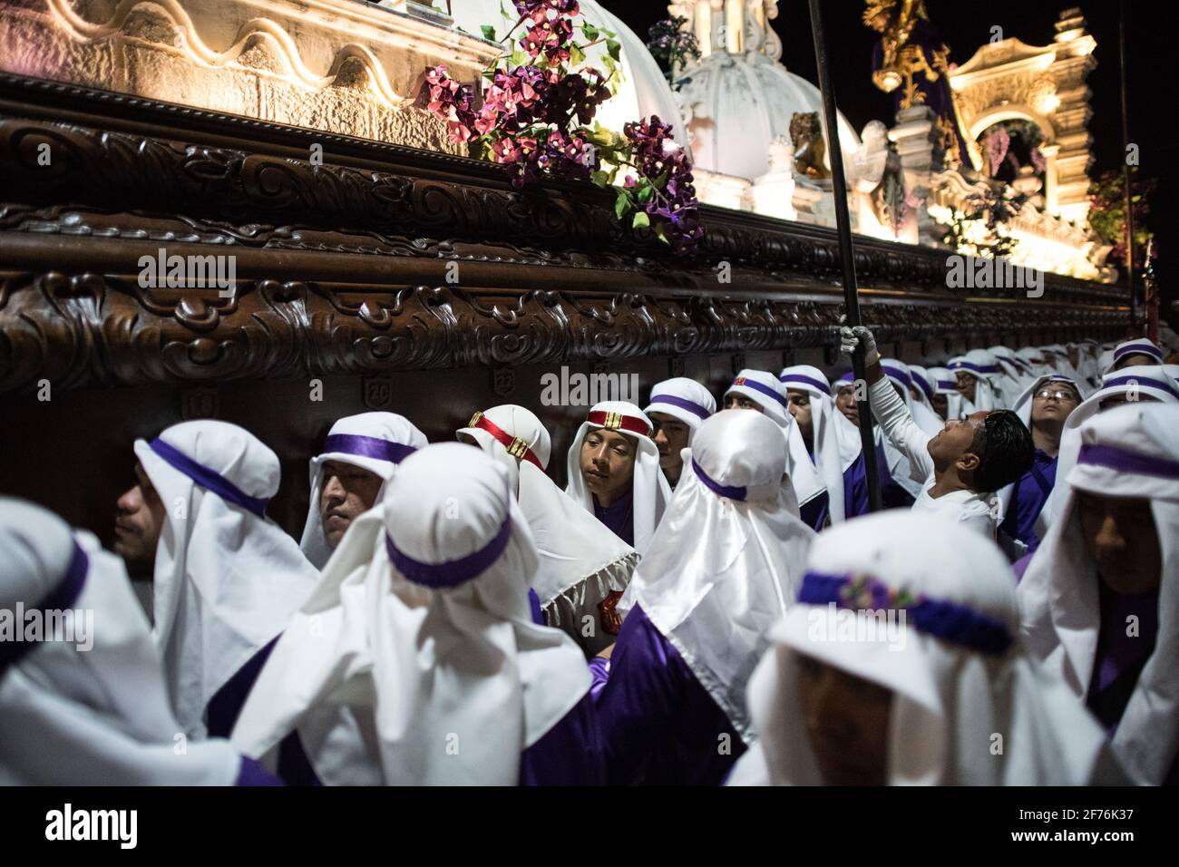 Cucuruchos in purple robes process solemnly through the streets of ...