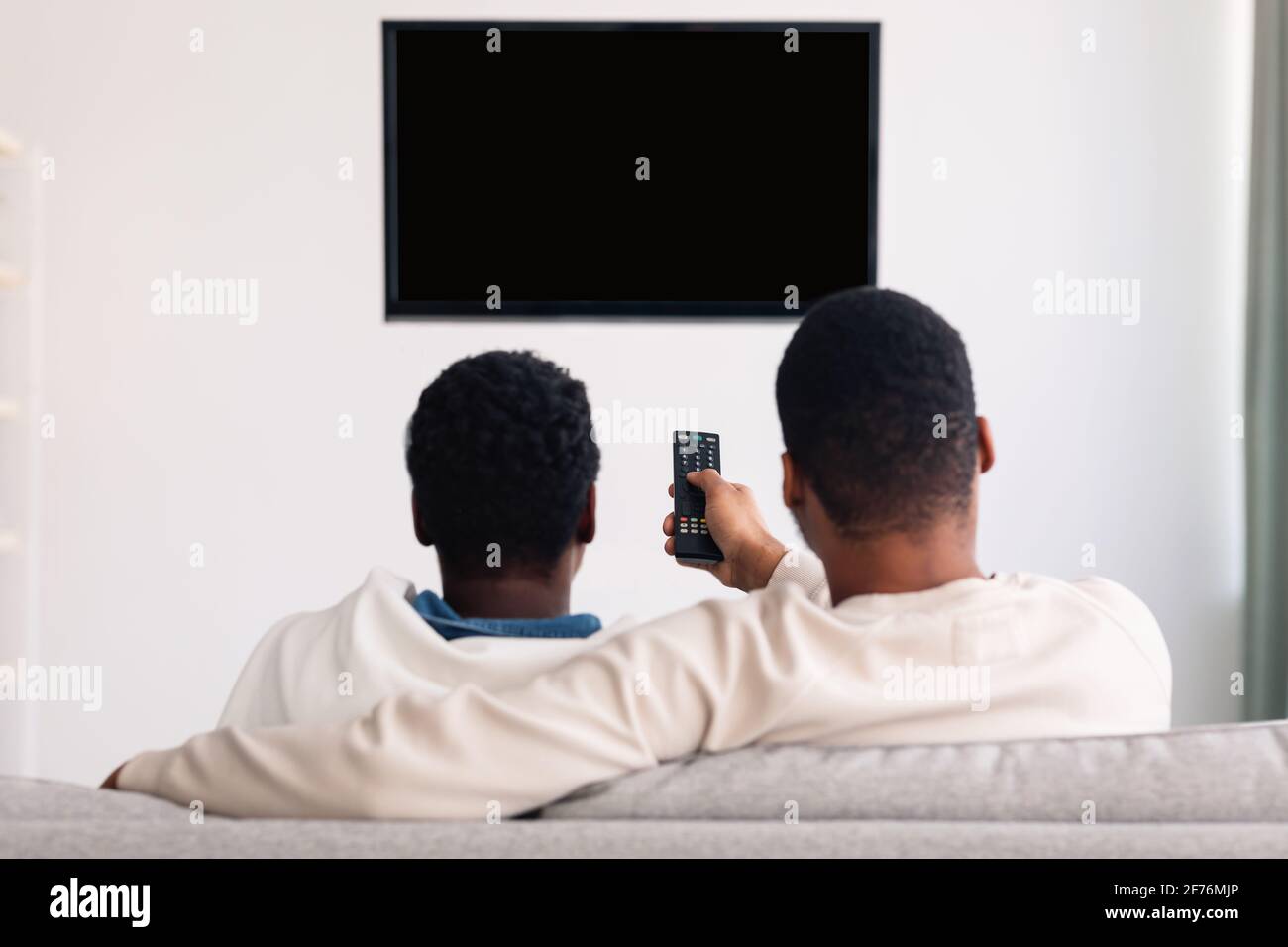 Black couple watching TV and using remote controller Stock Photo - Alamy