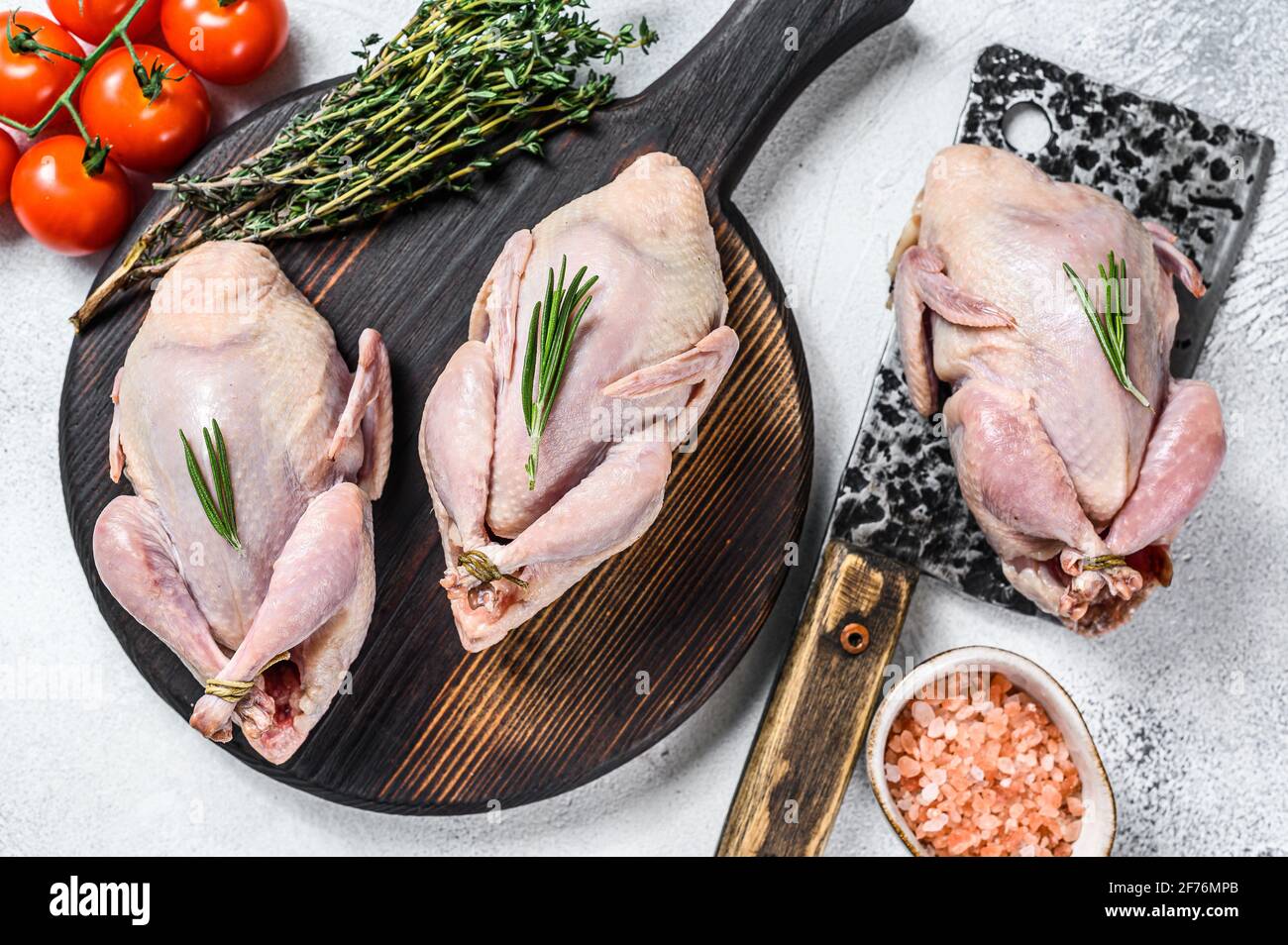 Raw quails preparation on a wooden cutting board with meat cleaver ...