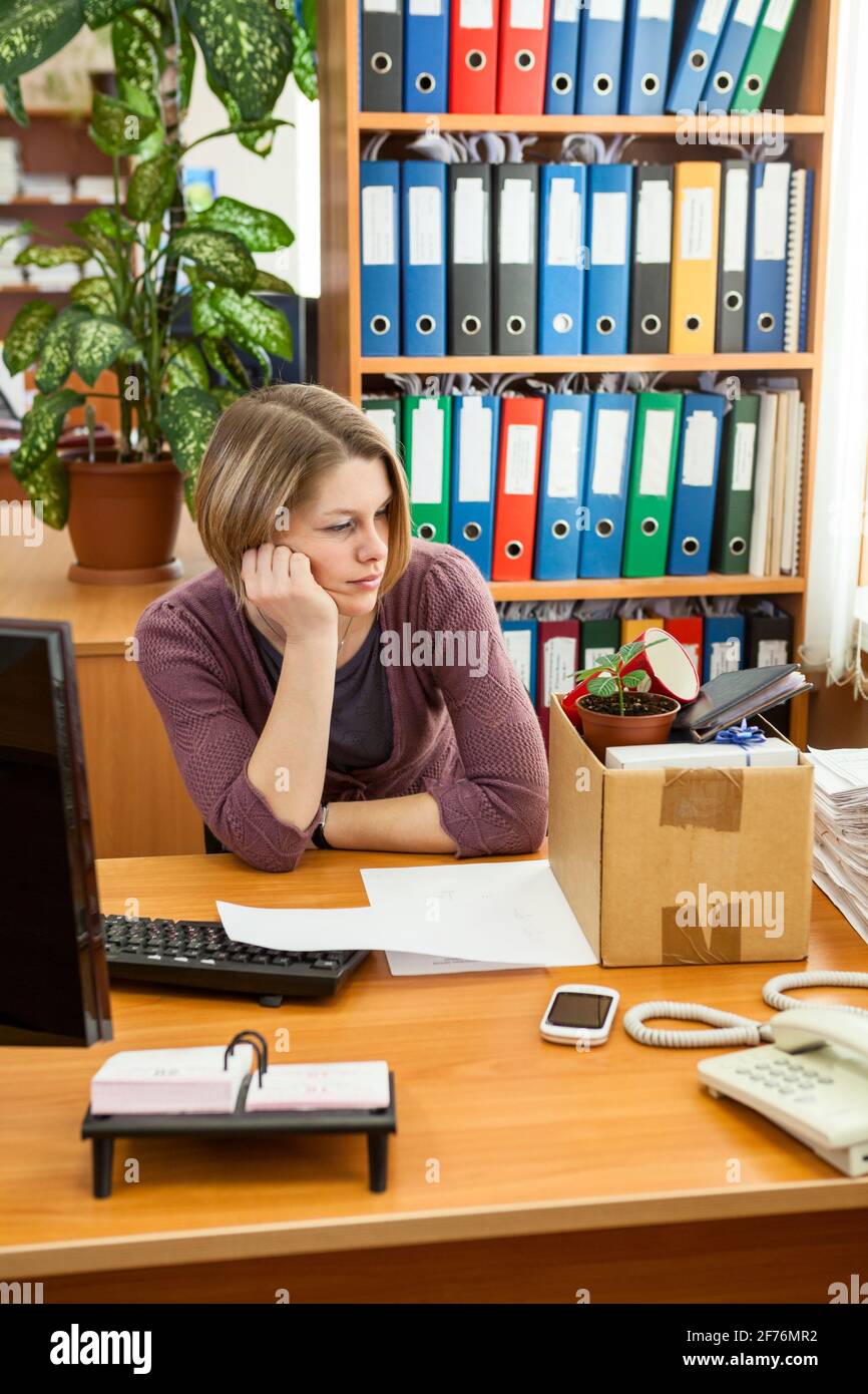 Upset dismissed young woman employee with packed box at workplace on ...