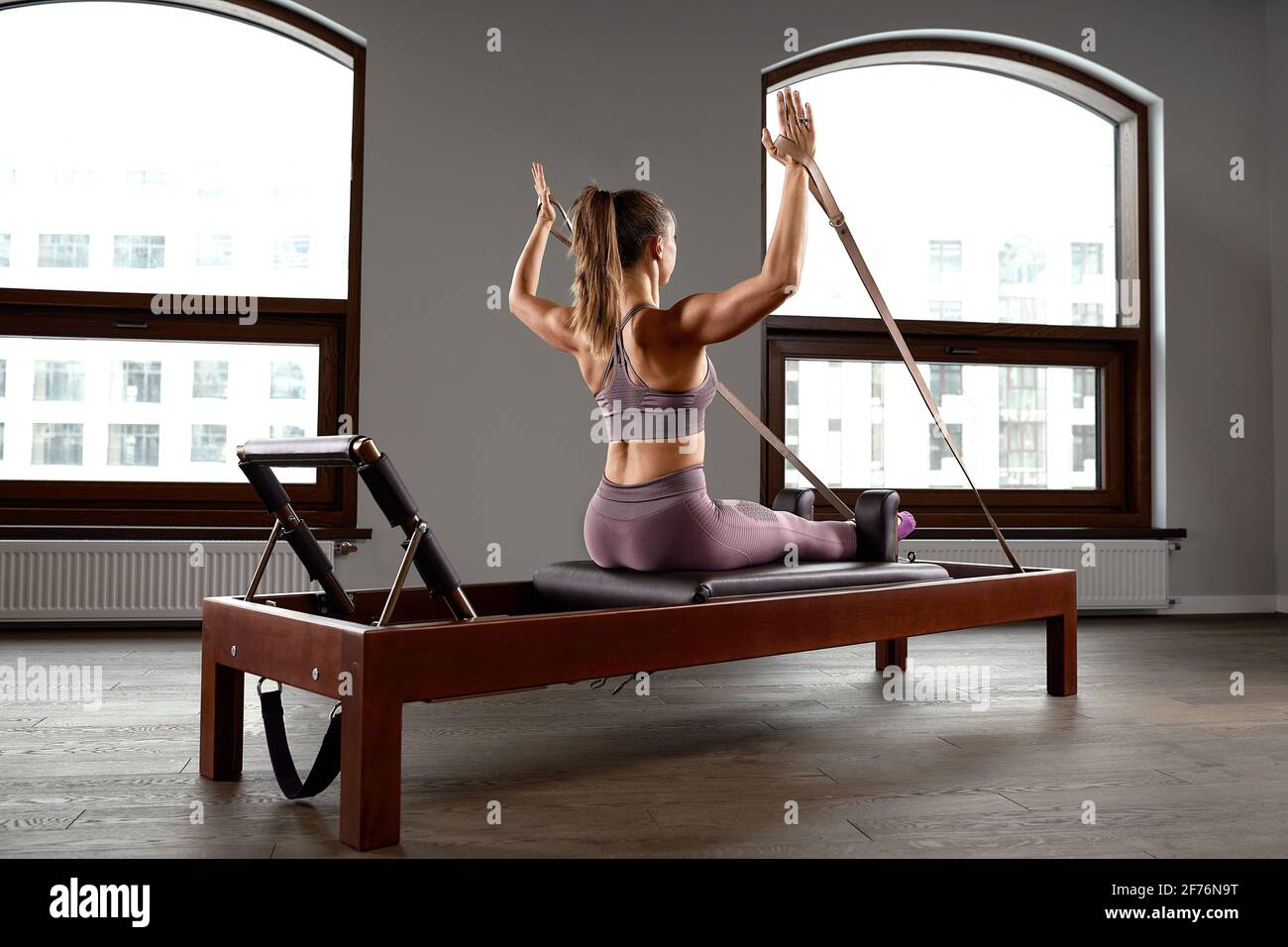 Young girl doing pilates exercises with a reformer bed. Beautiful slim ...