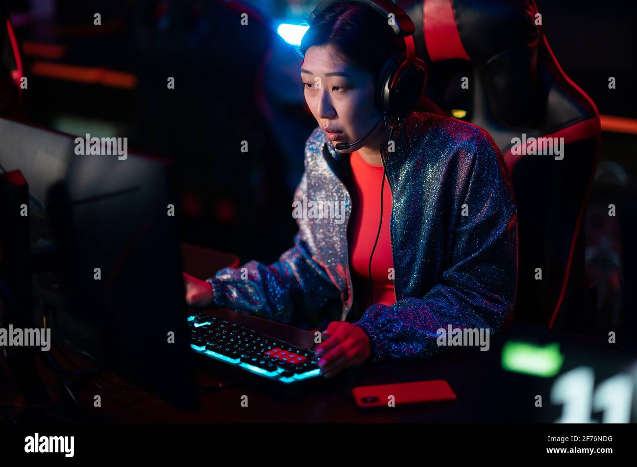A young asian gamer wearing a headset and headphones on her head trains ...