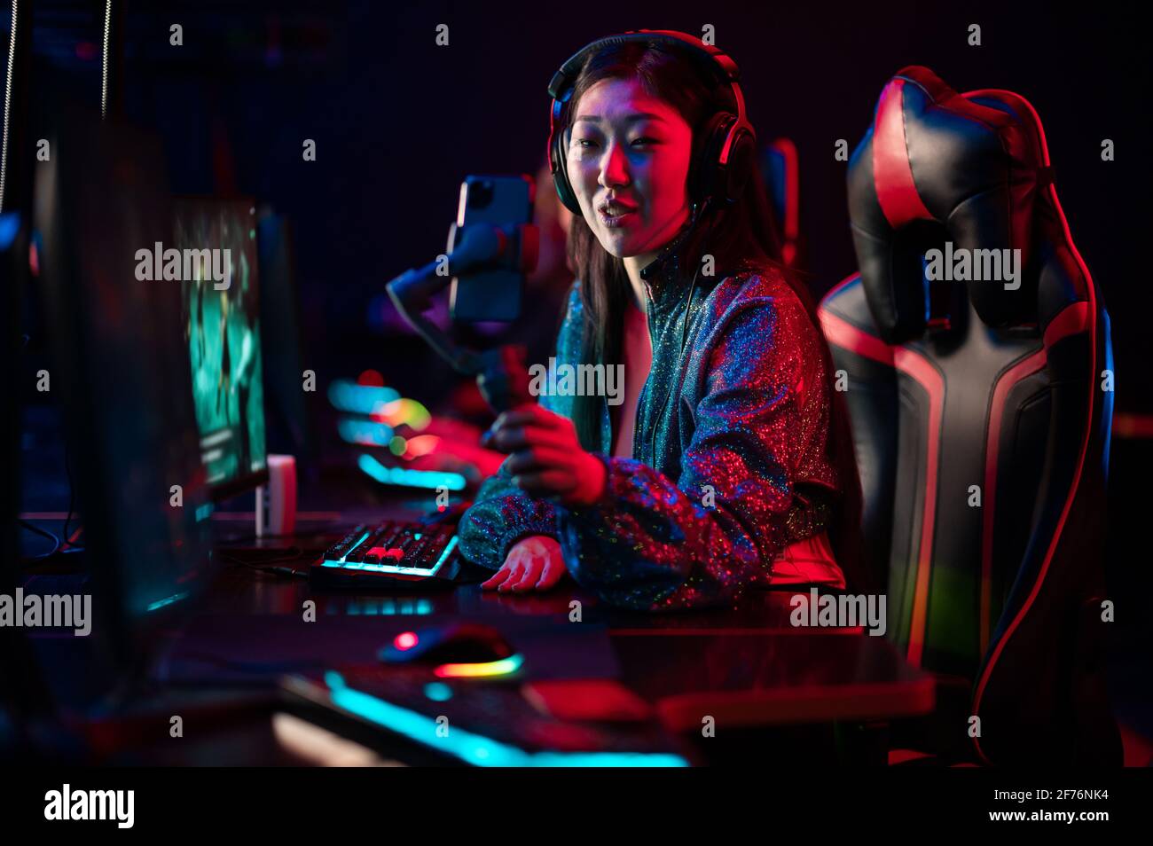 A young beautiful asian girl is broadcasting online on a smartphone ...