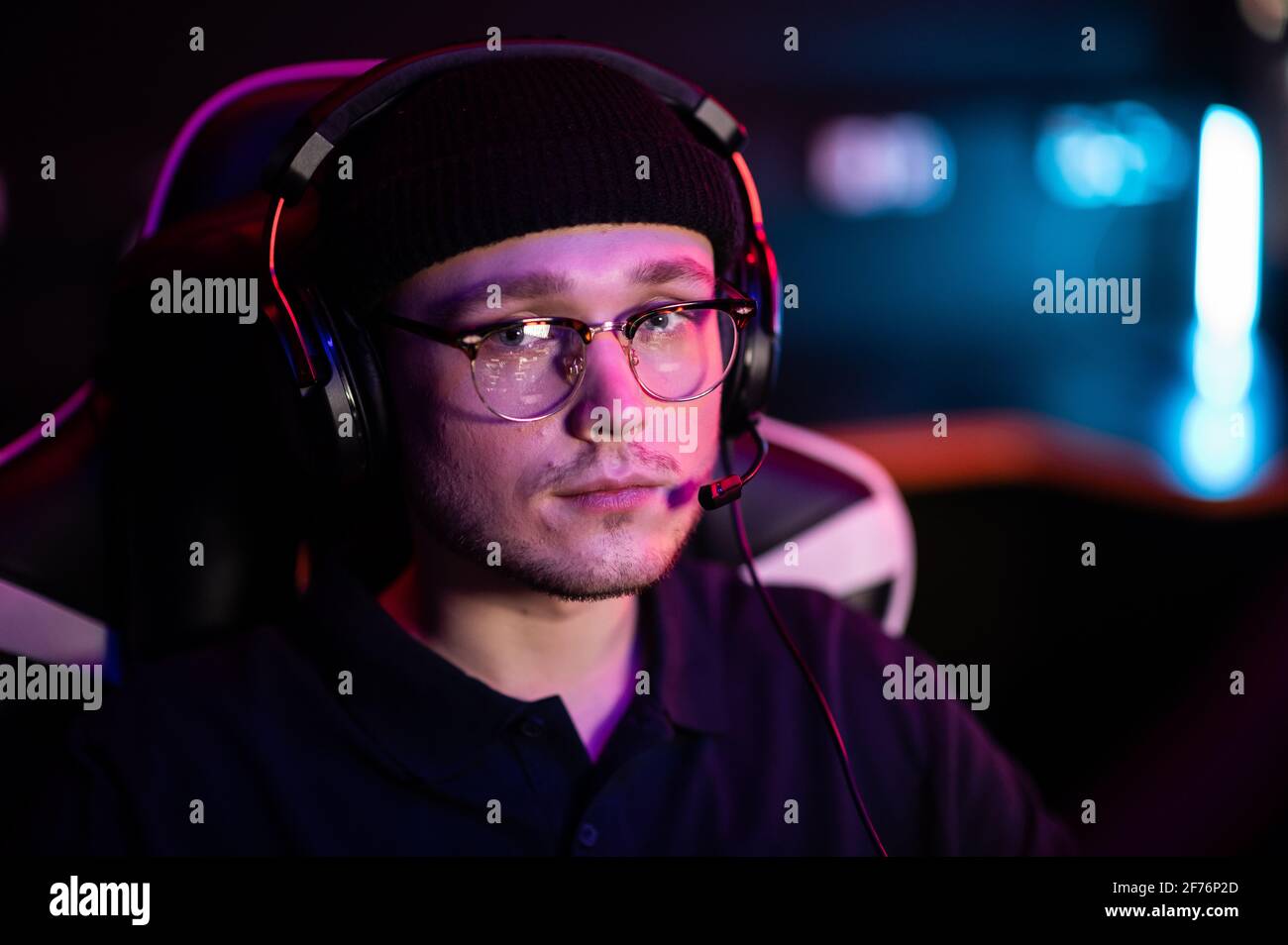 A young cyberathlete wearing glasses and a headset at an esports ...
