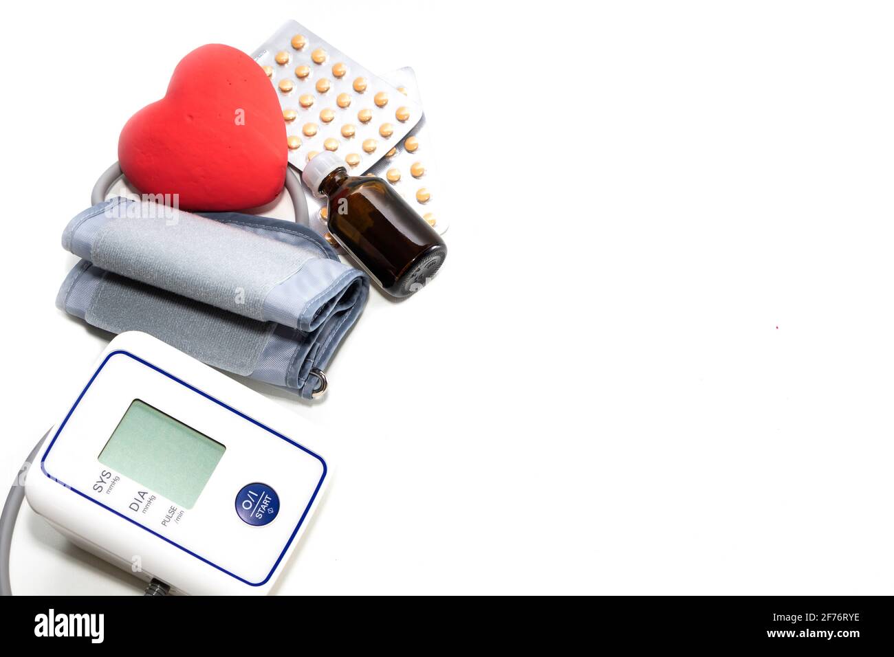 White electric blood pressure monitor, red heart and pills on a white ...