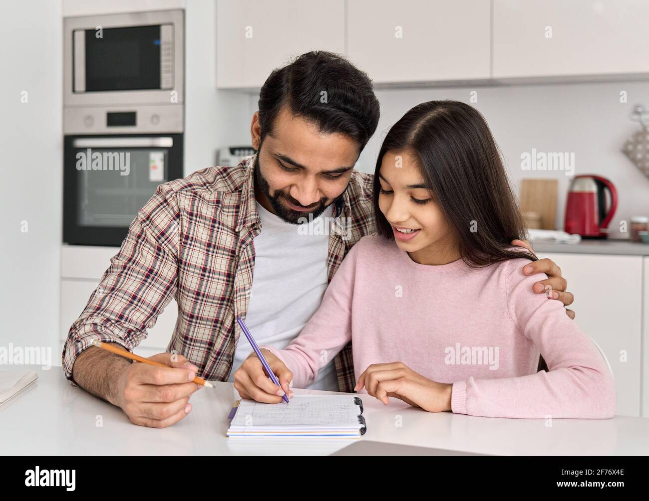 Happy indian father helping school child teen daughter studying at home ...
