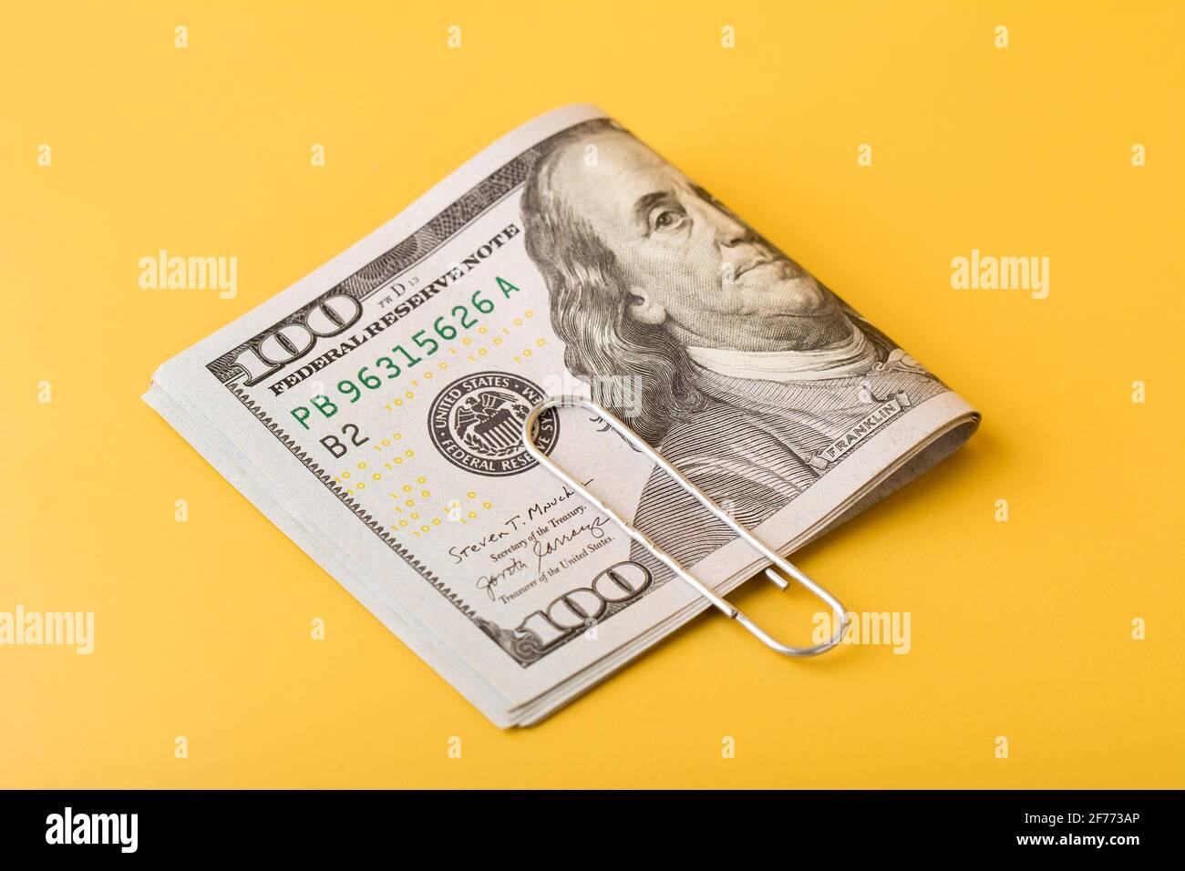 The 100 dollar bills are folded in half and held together with a paper ...