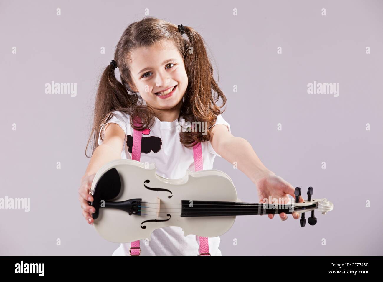 Female child playing the violin with gray background Stock Photo - Alamy