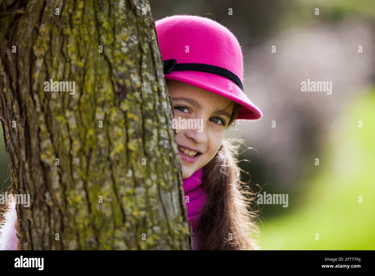 Beautiful child peeking behind a tree Stock Photo - Alamy