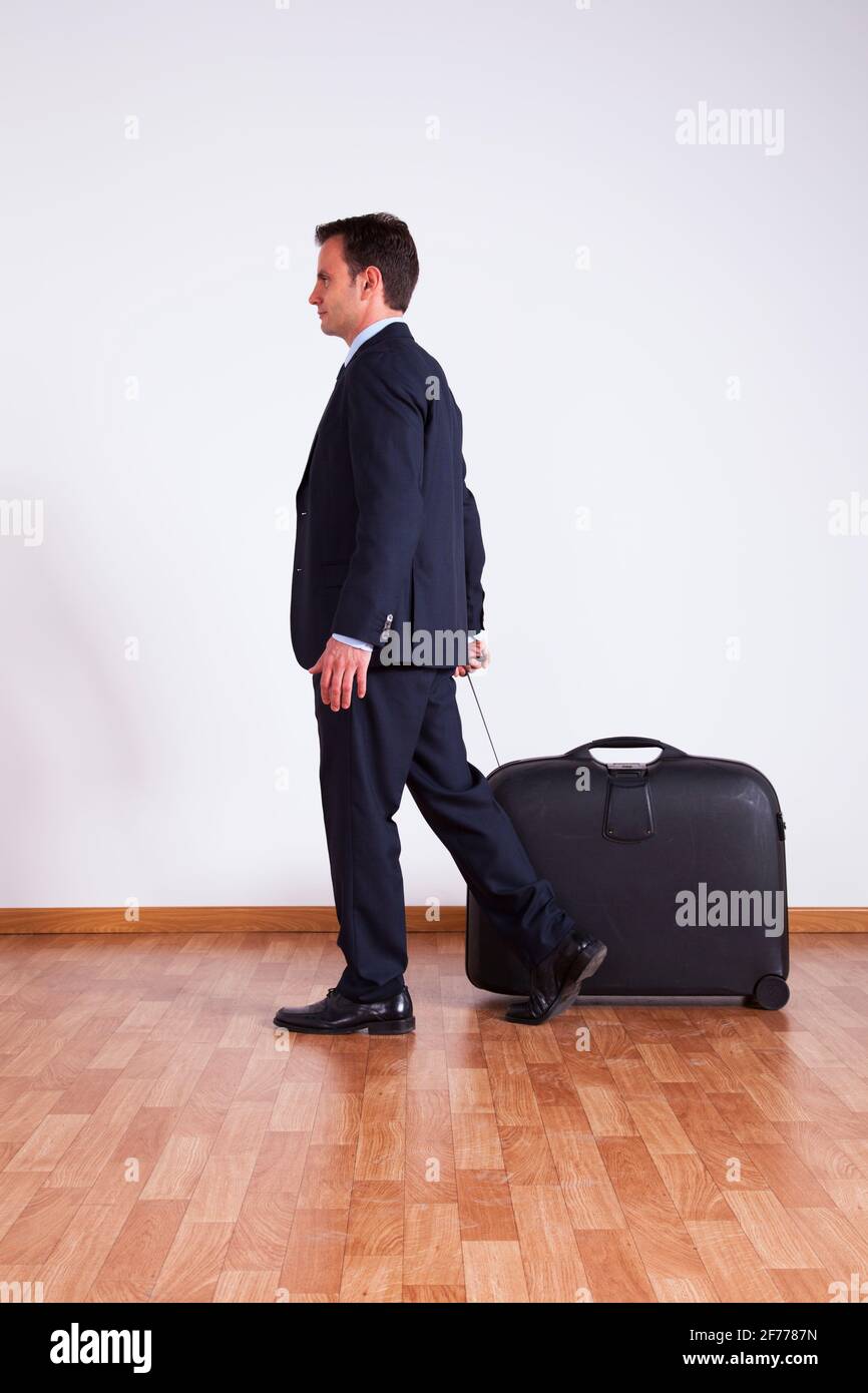 Businessman pulling his luggage Stock Photo - Alamy