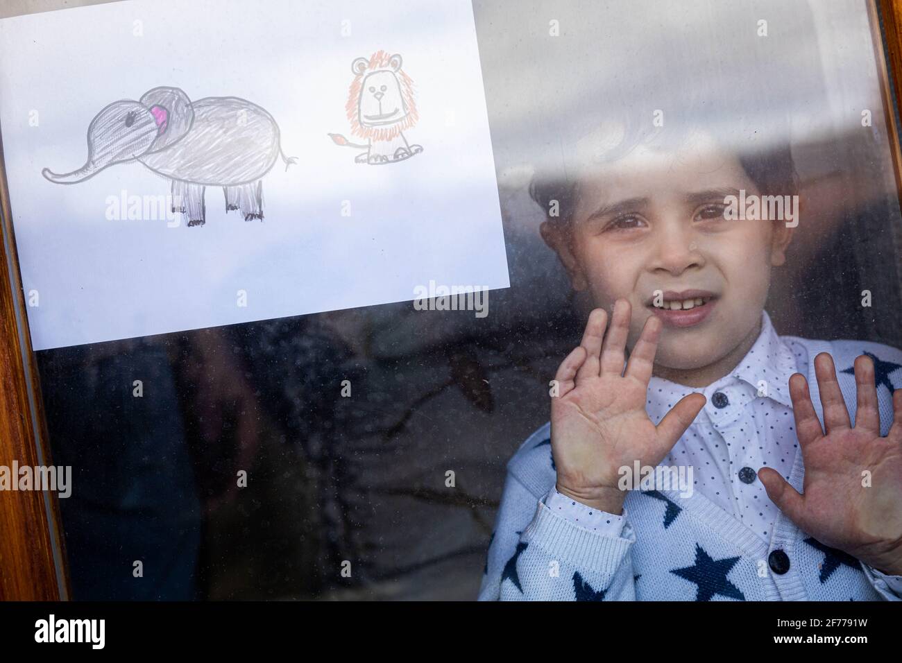 Cute, little boy looking through the window from inside with his ...