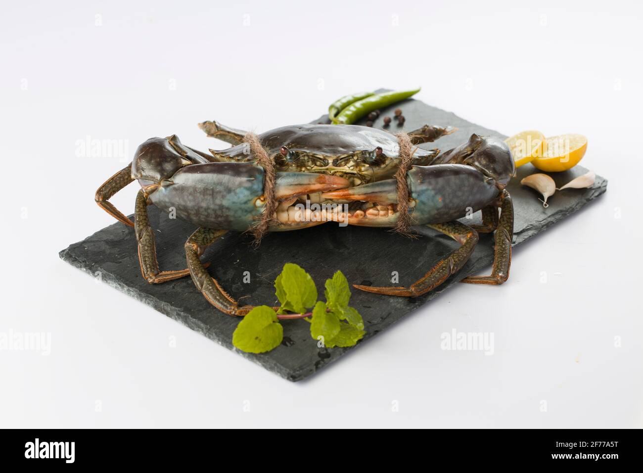 Live mud crab, arranged on a slate and garnished with lemon slices ...
