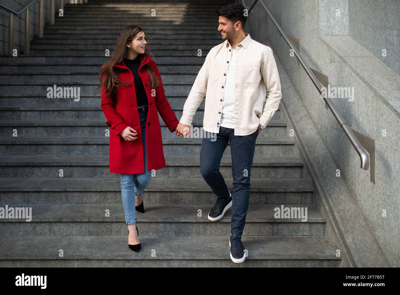 Happy couple walking down a staircase together Stock Photo - Alamy
