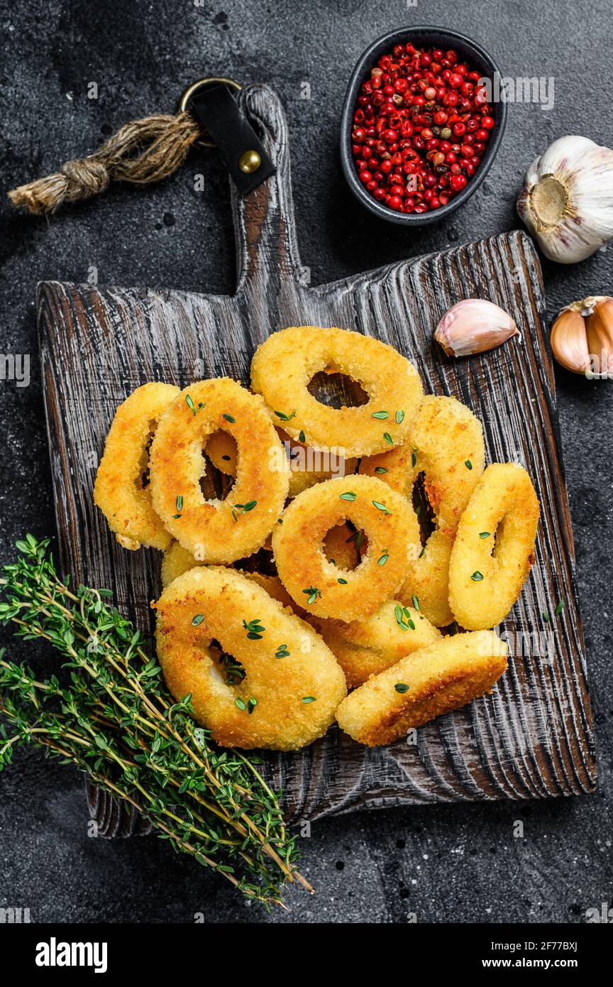 Deep fried squid calamari rings breaded on a cutting board. Black ...