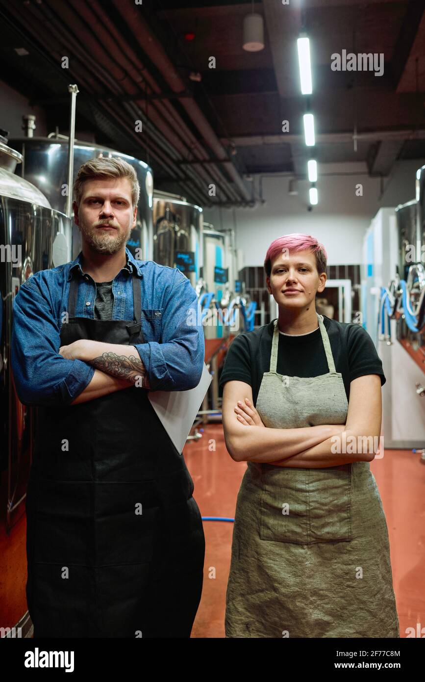 Young serious workers of contemporary beer production factory crossing ...