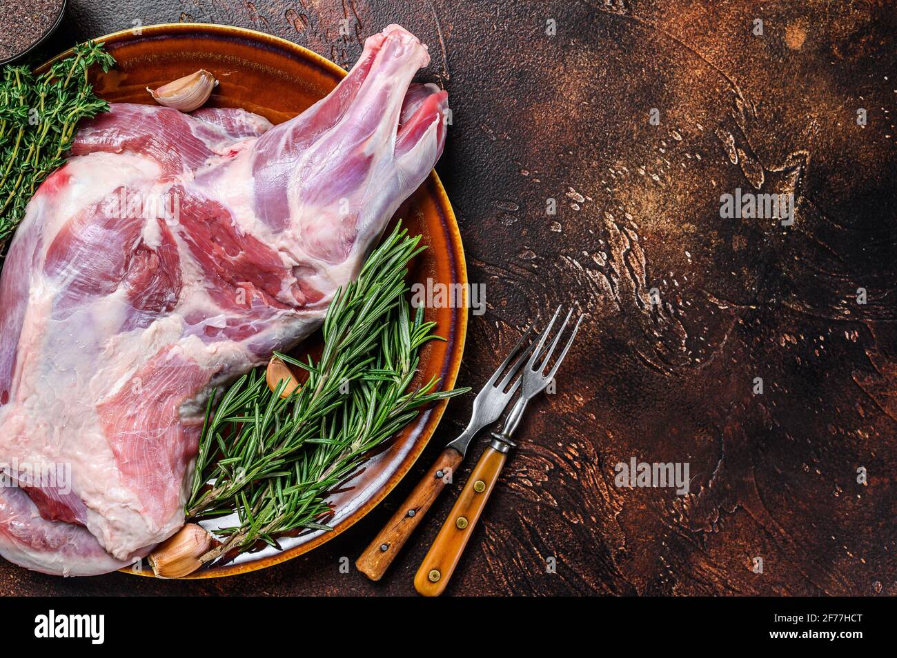 Whole fresh Raw lamb shoulder meat on a plate. Dark wooden background ...