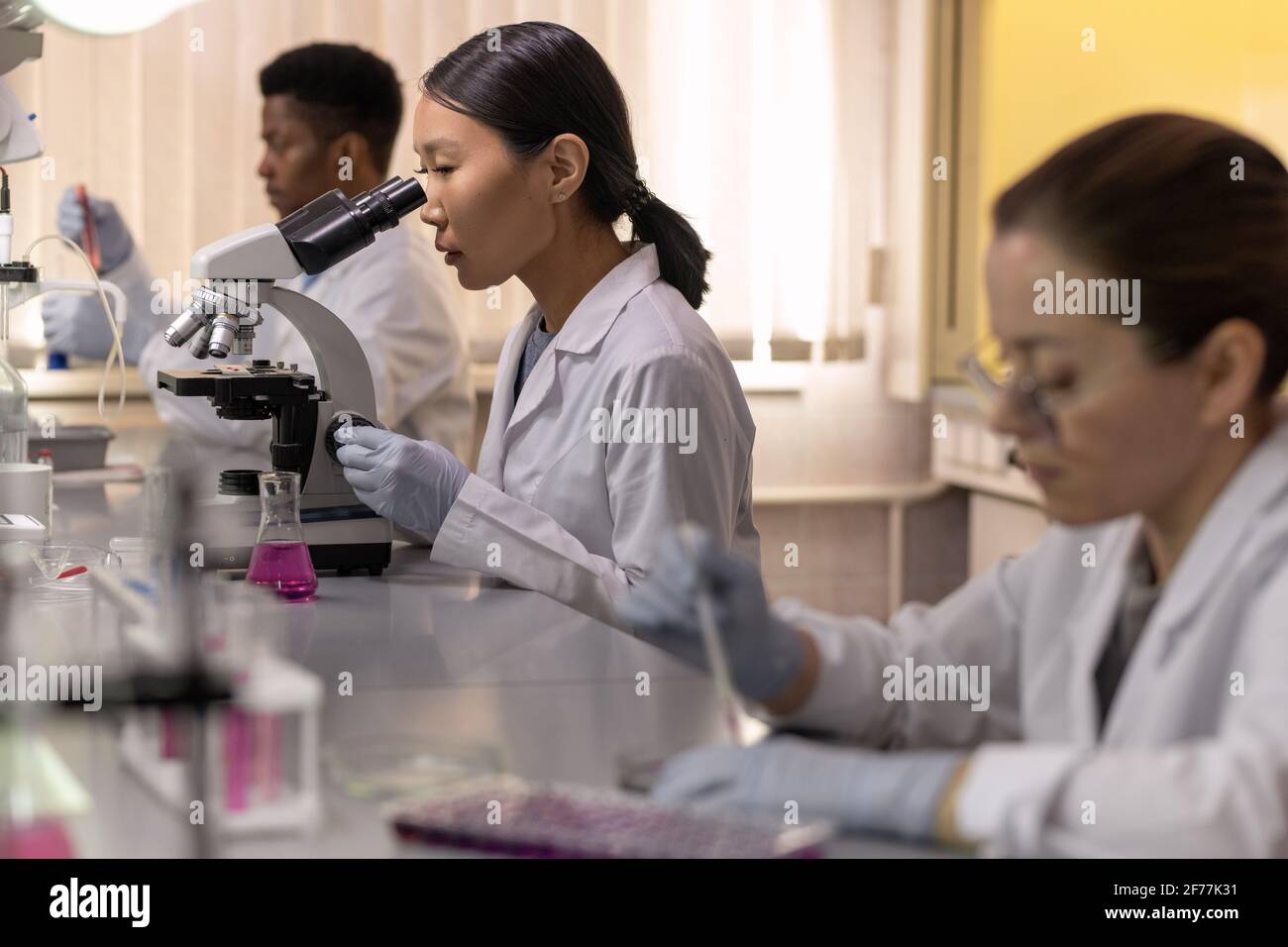 Asian young scientist looking through the microscope while working at ...