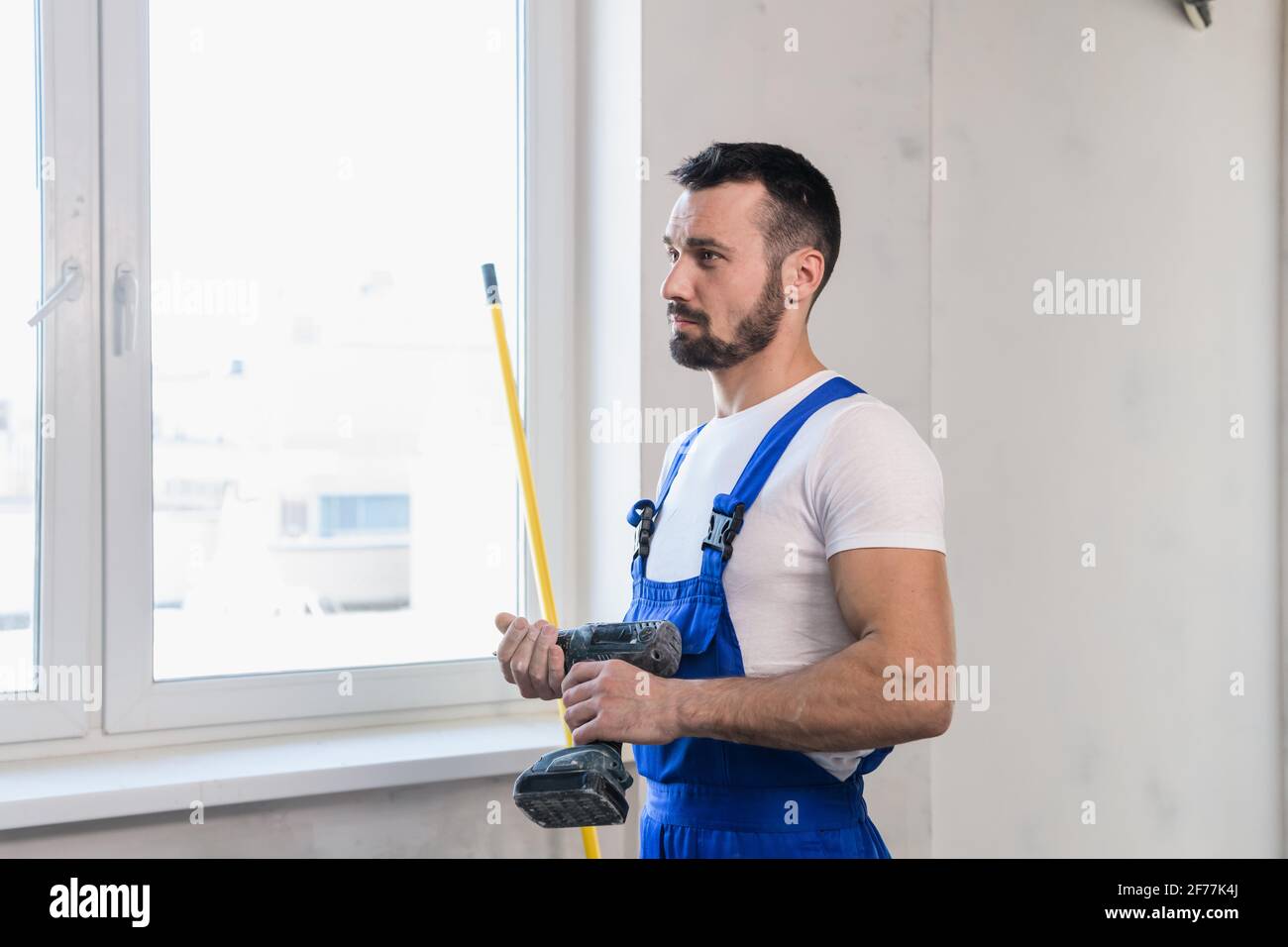 A repairer in a blue overalls holds a tape measure in his hand Stock ...
