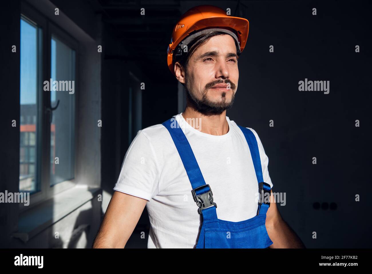The workman puts an hard hat on his head. He is dressed in blue ...