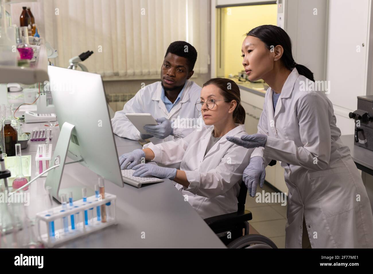 Group of scientists sitting at the table looking at computer monitor ...