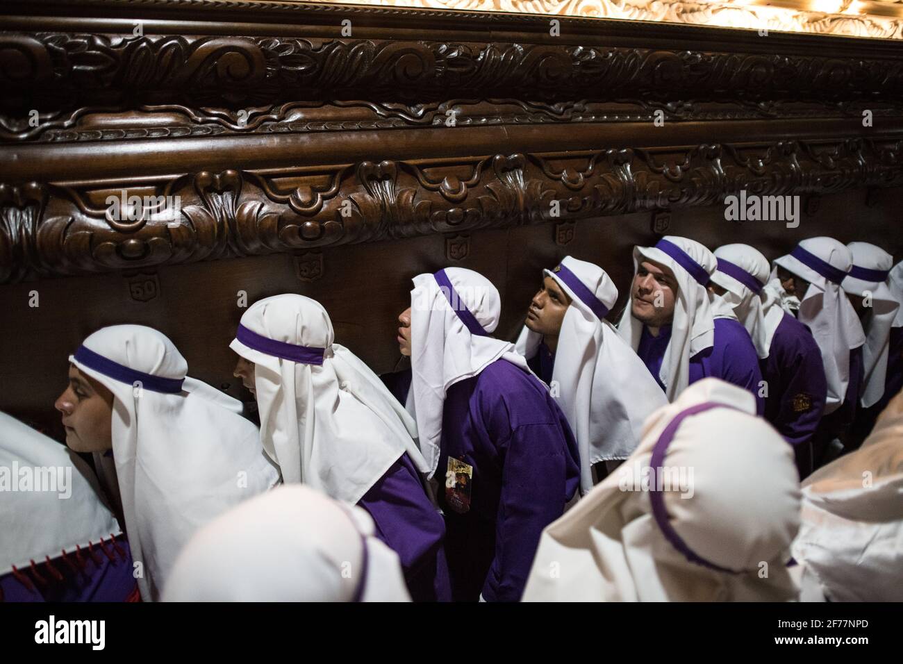 Cucuruchos in purple robes process solemnly through the streets of ...