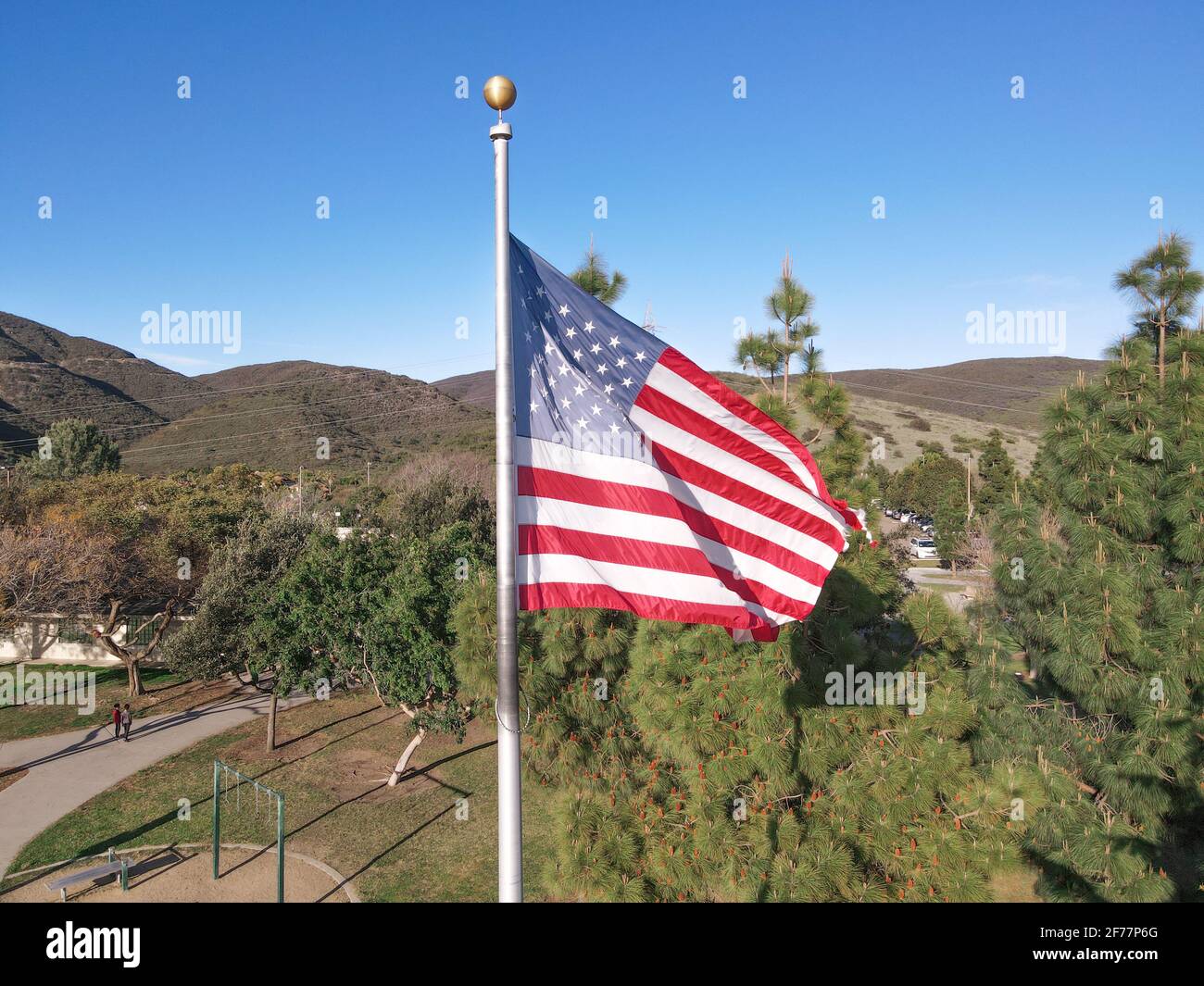 Pole with waving glory American flag surrounded by trees on the top of ...