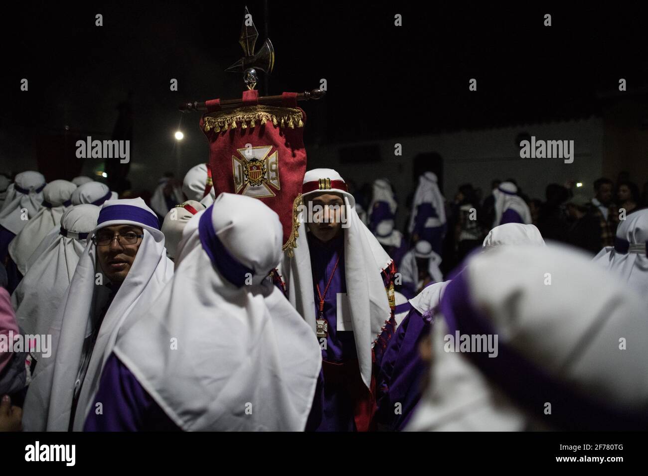 Cucuruchos in purple robes process solemnly through the streets of ...