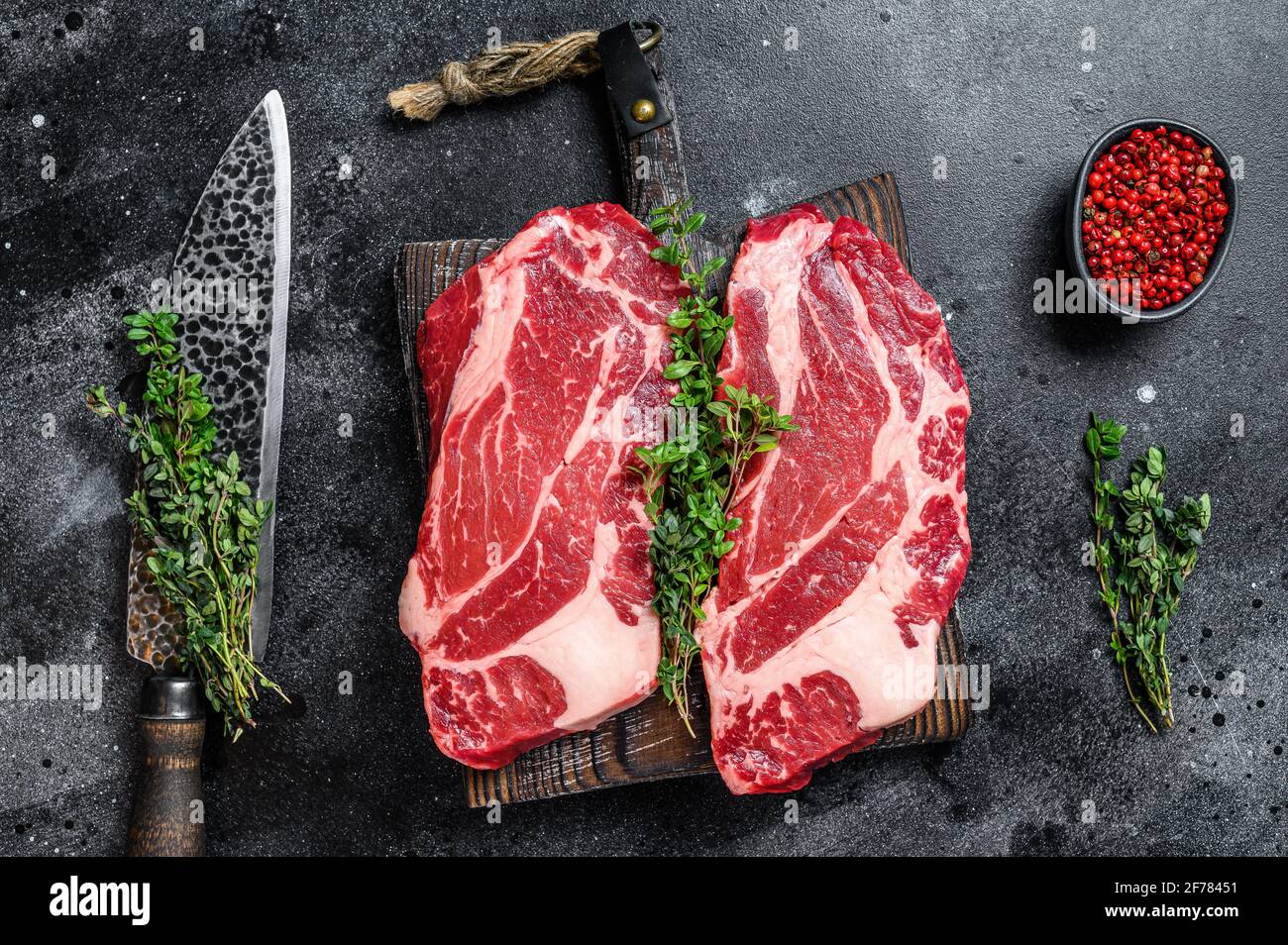 Raw chuck eye roll steaks premium beef meat on a cutting board. Black ...