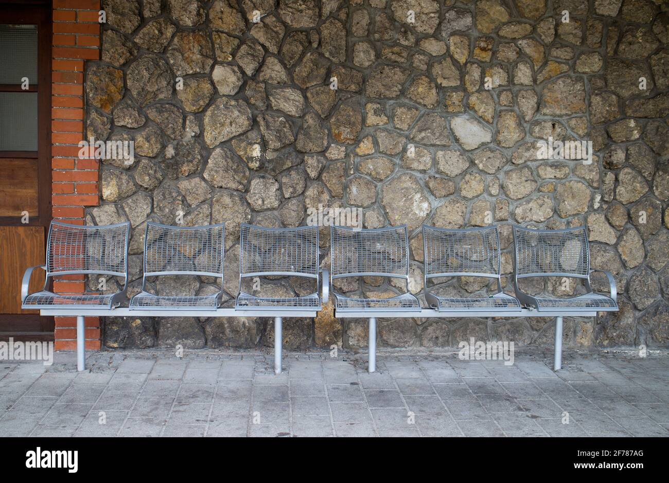 Metal bench in the waiting area on the platform of a train station ...