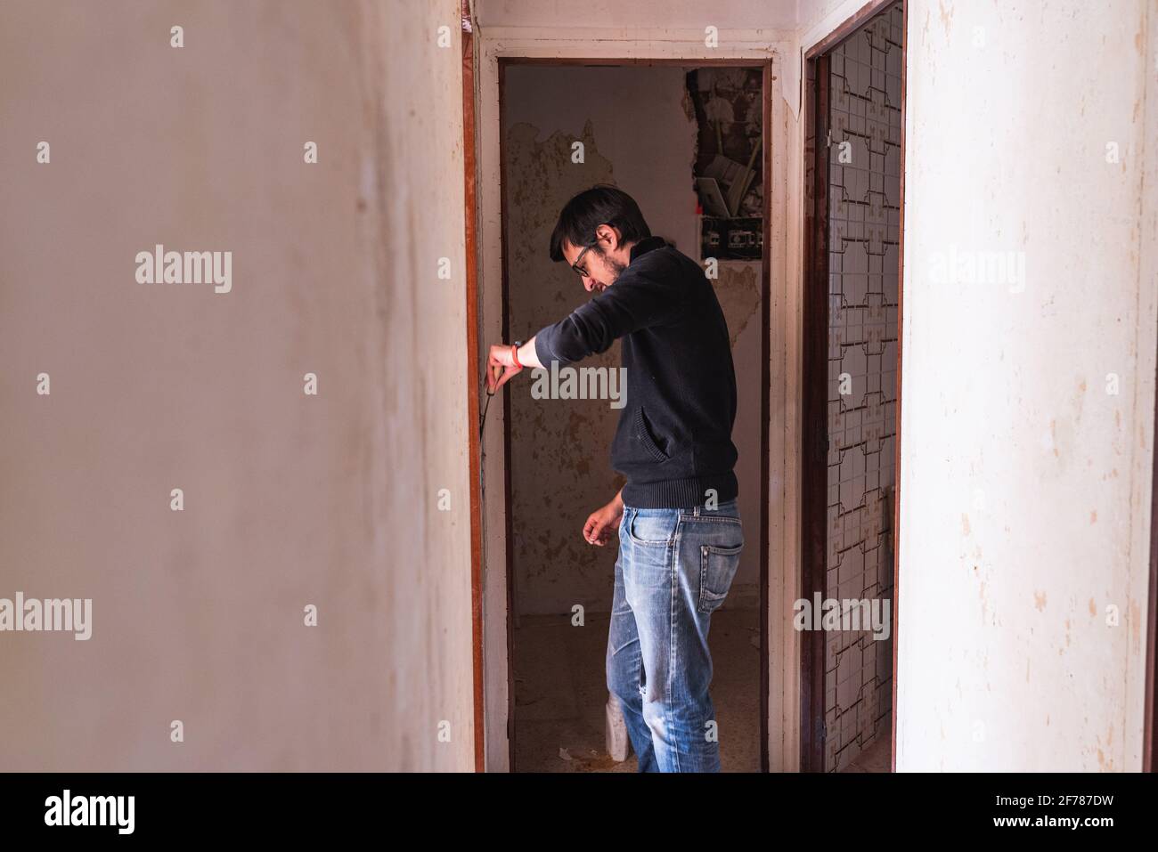 Man removing wallpaper from a hallway wall with a scraper. Works at ...