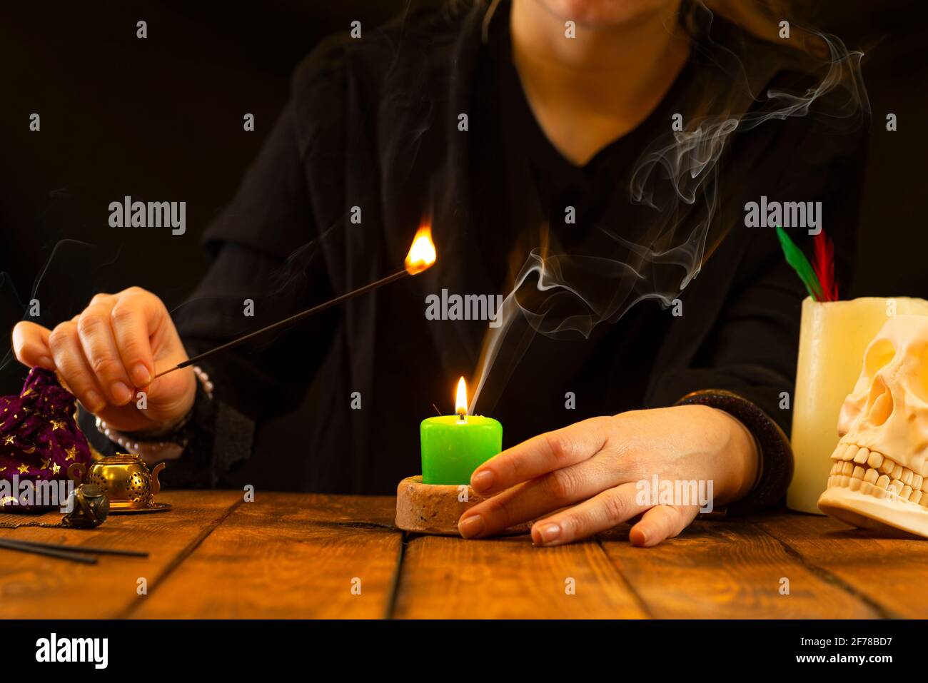 A fortune teller or oracle with objects for fortune-telling lights a ...