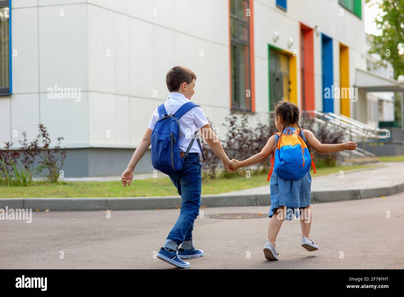 two schoolchildren, a little girl and a boy in a white shirt with ...