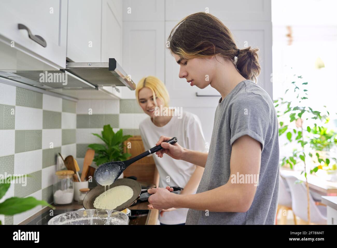 Teenagers guy and girl cooking pancakes on kitchen stove together Stock ...