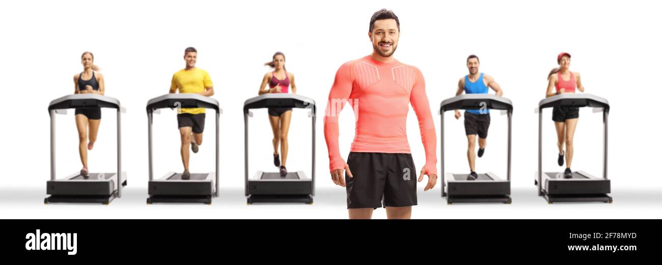 Fit muscular man posing with people running on treadmills in a row in ...