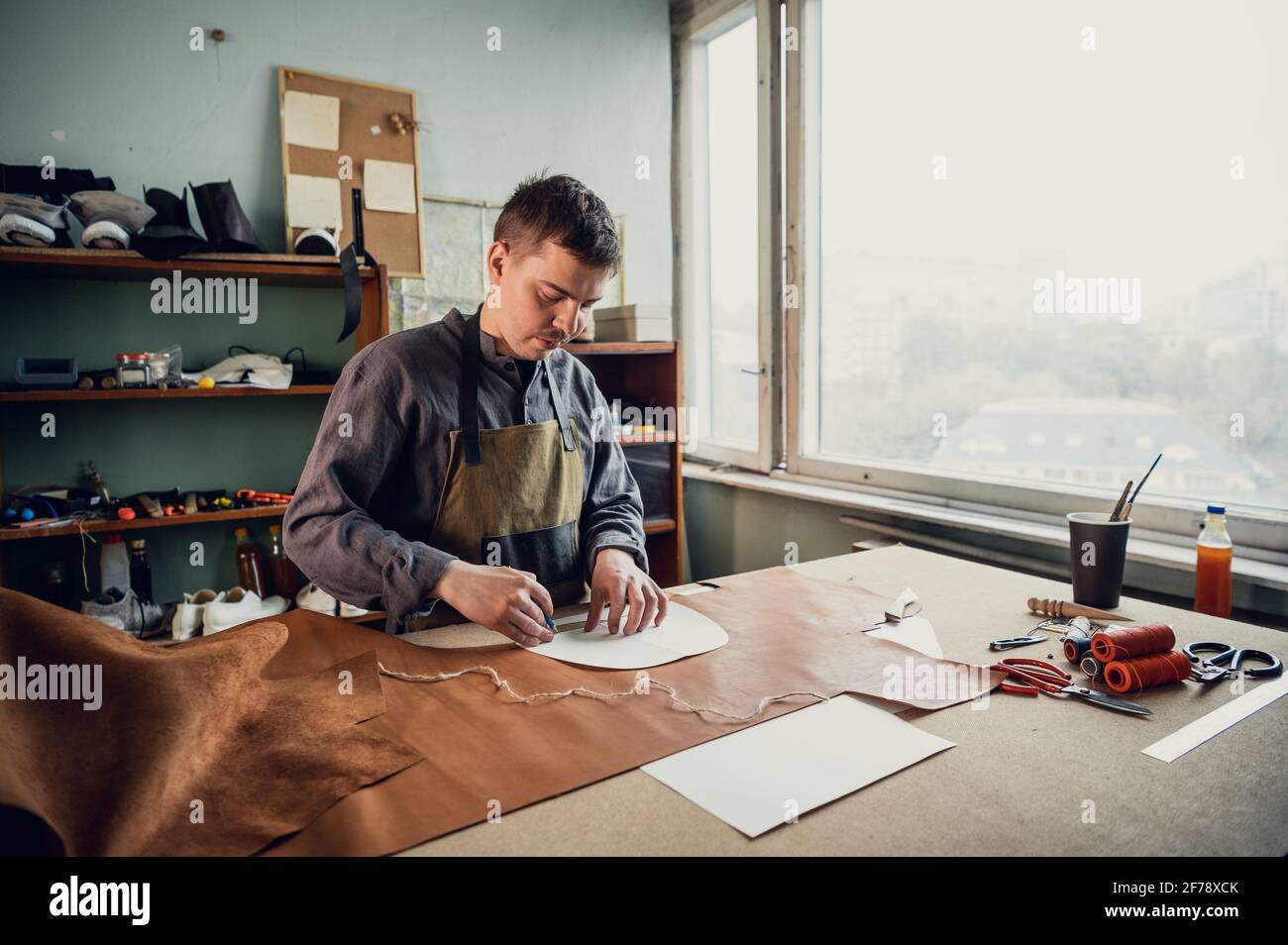 In the boot shop, an experienced shoemaker starts the process of ...