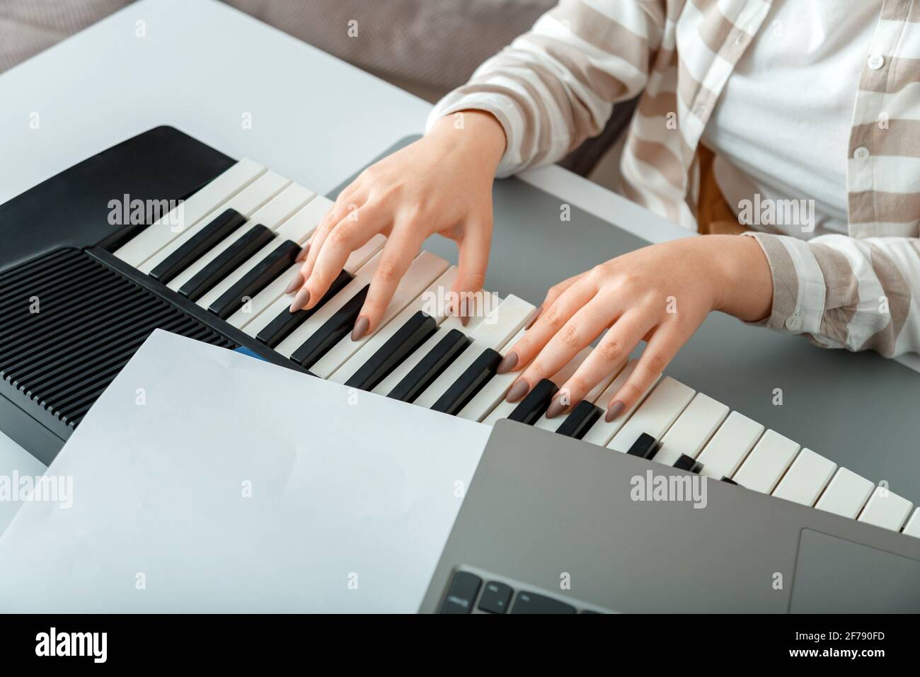 Woman playing piano record music on synthesizer using notes and laptop ...