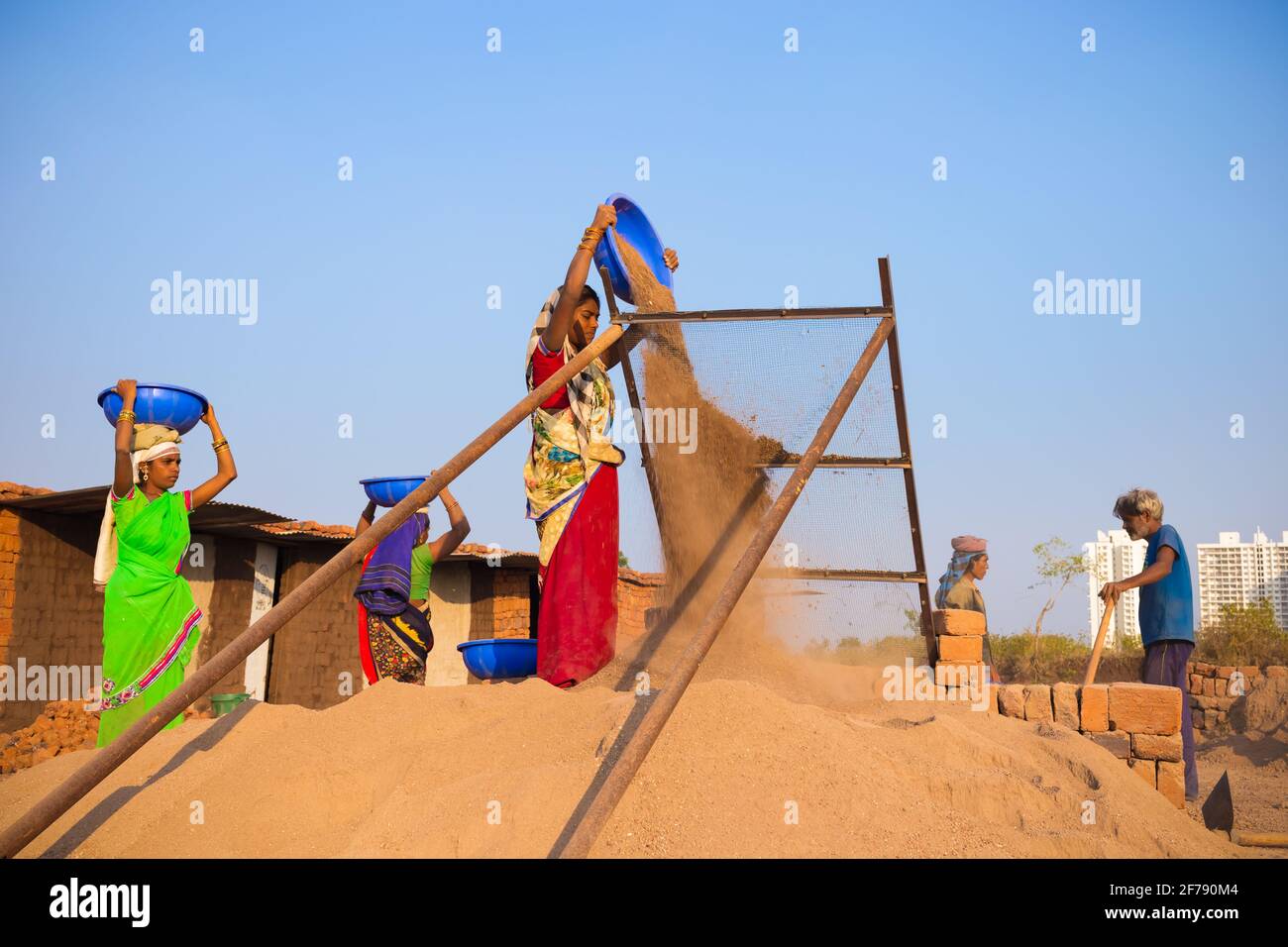 Women and men working in a brick kiln site, preparing the soil before ...