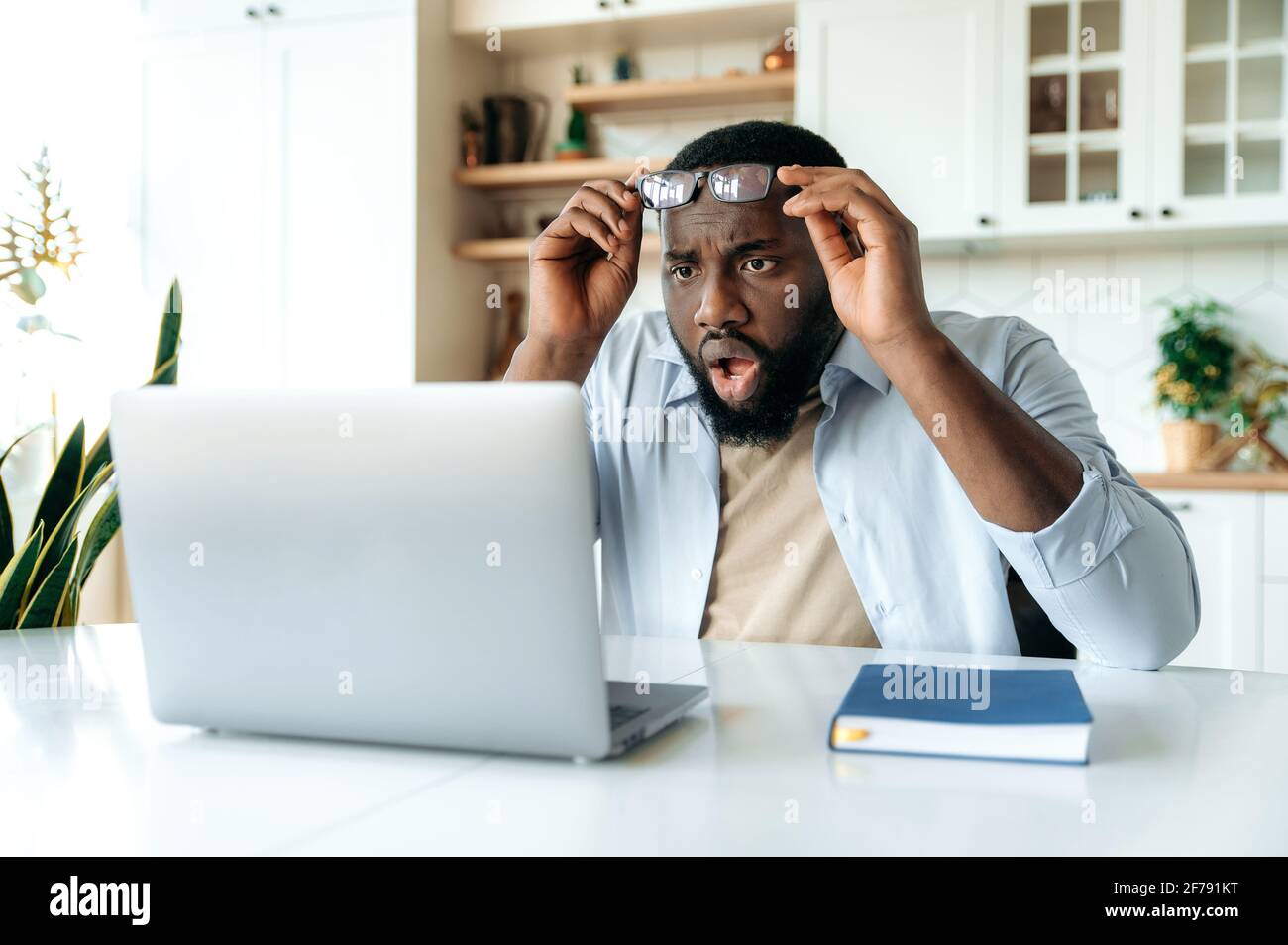 Shocked African American bearded businessman, manager or broker, sits ...