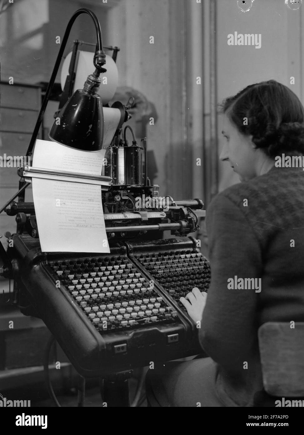 Woman at writing device / typewriter in factory environment Stock Photo ...